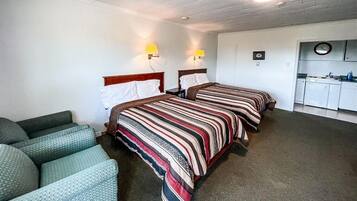 Quarto de hotel com duas camas, uma kitchenette e uma área de estar.