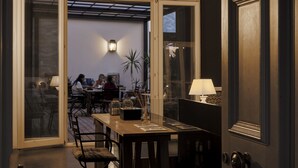 Porta de correr de vidro aberta, dando acesso a uma sala de jantar com mesa, cadeiras e luminária.