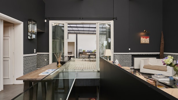 Cozinha moderna com ilha central, área de refeições com mesa e cadeiras, e sala de estar com sofá e mesinha de centro.