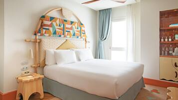 Uma cama bem arrumada com cabeceira estampada em padrão geométrico, mesa de cabeceira de madeira com telefone e um ventilador de teto.
