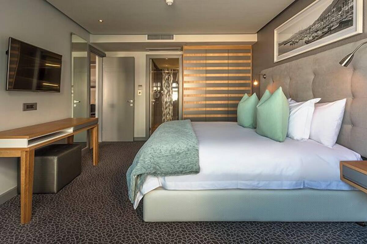 Quarto de hotel moderno com uma cama grande, uma escrivaninha e uma televisão.