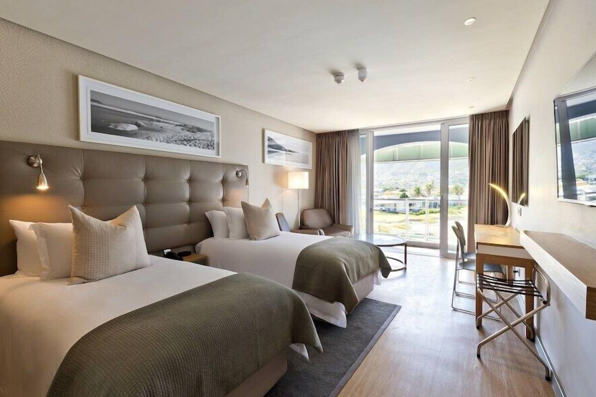 Quarto de hotel com duas camas, uma escrivaninha e vista para a paisagem urbana.