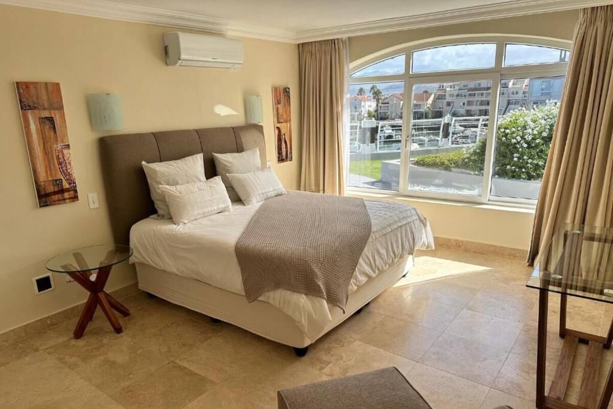 Quarto com uma cama grande, uma mesa de vidro e vista para o exterior.