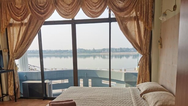 Quarto com cama, cortinas e vista para um lago.
