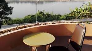 Varanda com mesa e cadeira, dando para um lago calmo e uma linha de costa distante.