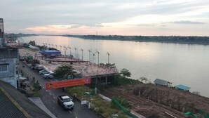 Vista do rio com uma ponte, carros estacionados e uma roda gigante.