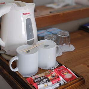 Uma bandeja com uma chaleira Express da Tefal, duas canecas brancas e embalagens de café Nescafe e Doğus.