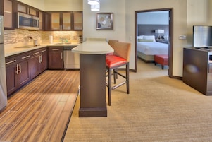 Quarto de hotel com cozinha compacta, cama, televisão e banheiro.