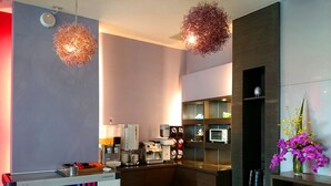 Um lobby de hotel moderno com um espaço para café, micro-ondas e prateleiras decorativas.