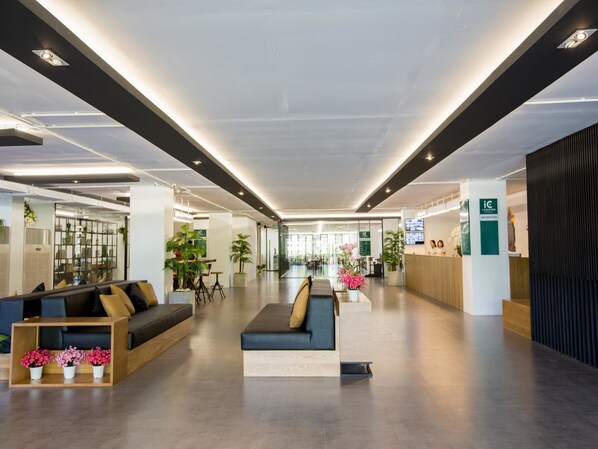 Um lobby moderno com balcão de recepção, área de estar e plantas em vasos.
