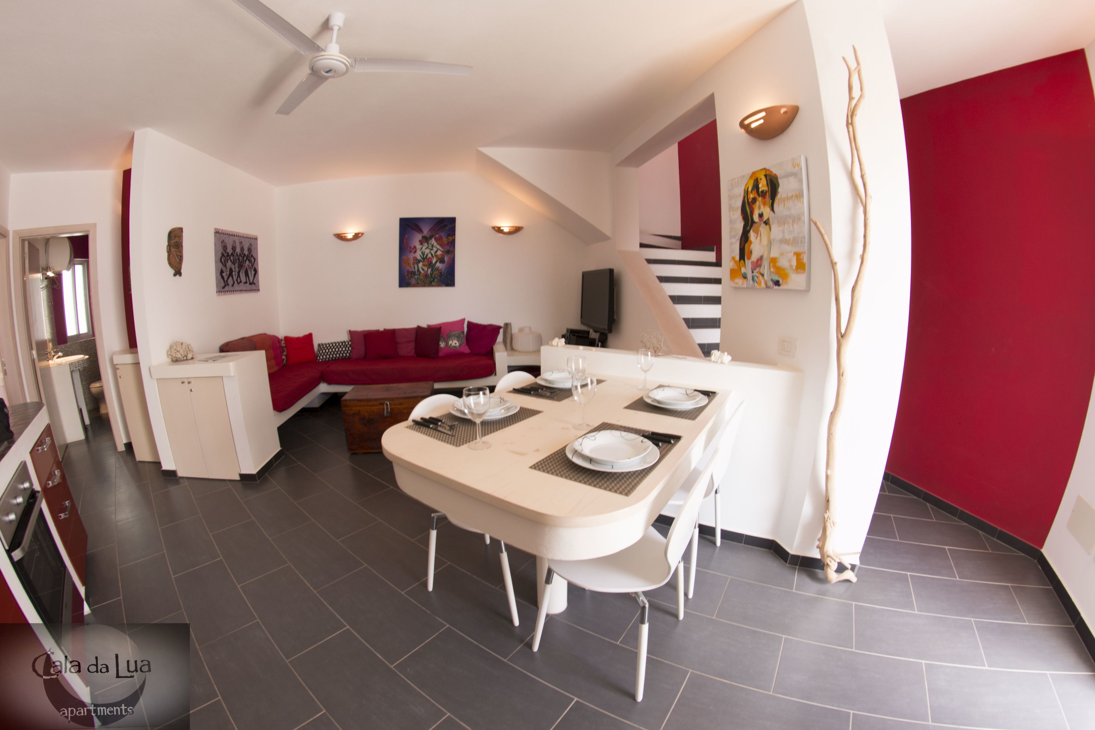 Uma sala moderna com área de jantar, paredes vermelhas e uma escada.