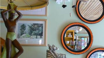 Quarto com escultura de madeira, obra de arte emoldurada e vários espelhos com bordas laranja.