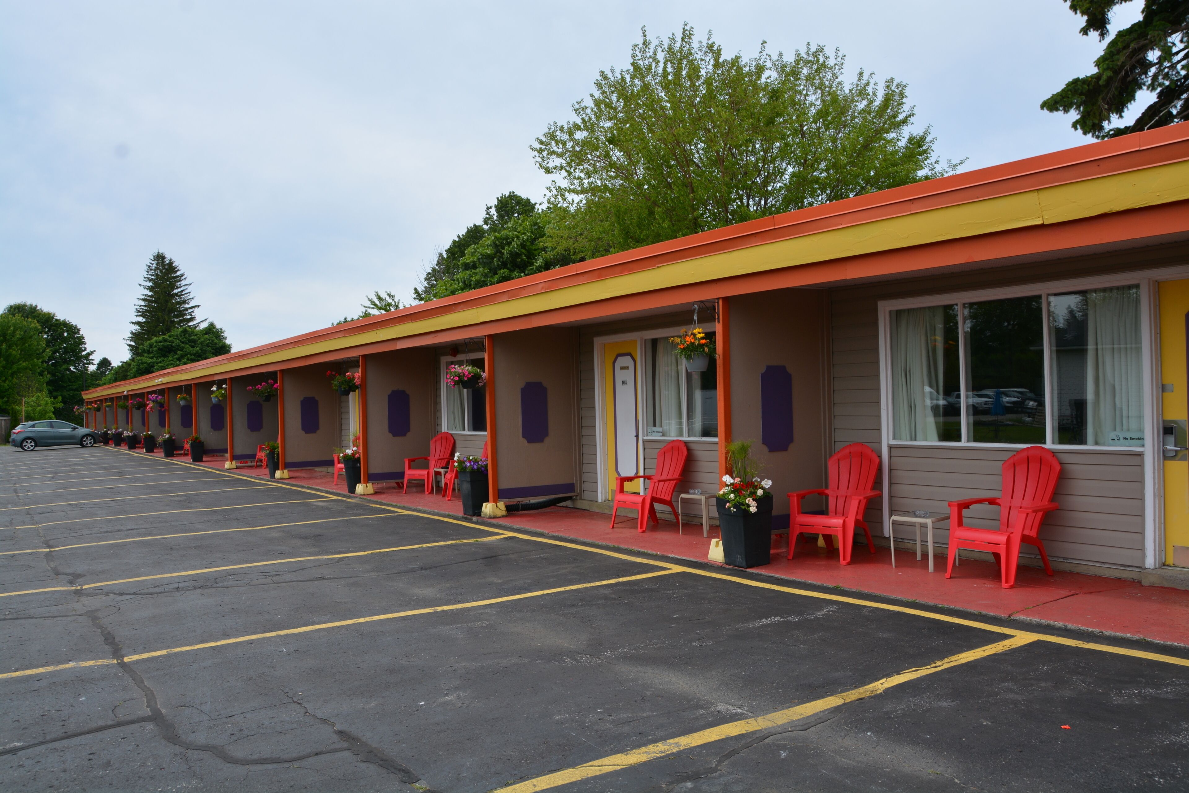 Um motel com uma fileira de quartos, cada um com janela e porta.