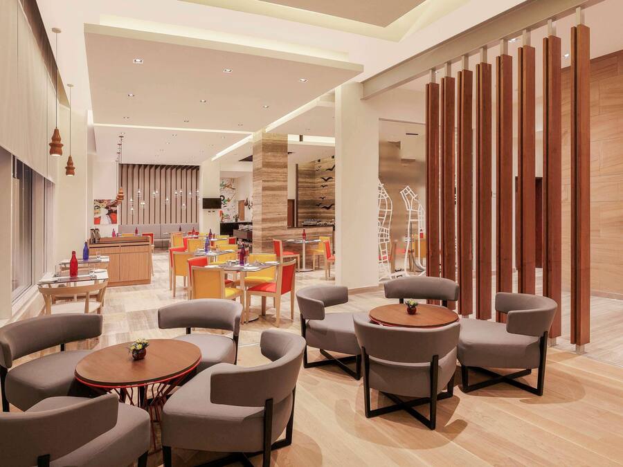 Um hall de hotel moderno com área de estar central, balcão de recepção e parede decorativa com ripas verticais de madeira.