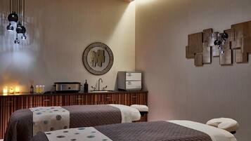 Quarto de hotel com duas camas, uma toucador com espelho, pia e uma pequena cozinha.