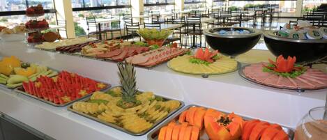 Buffet com diversos alimentos, incluindo frutas, legumes e carnes.