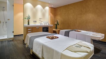 Quarto de hotel moderno com duas camas, área de chuveiro e toucador com espelho.
