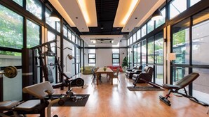 Uma academia espaçosa com equipamentos de ginástica, janelas amplas e piso de madeira.