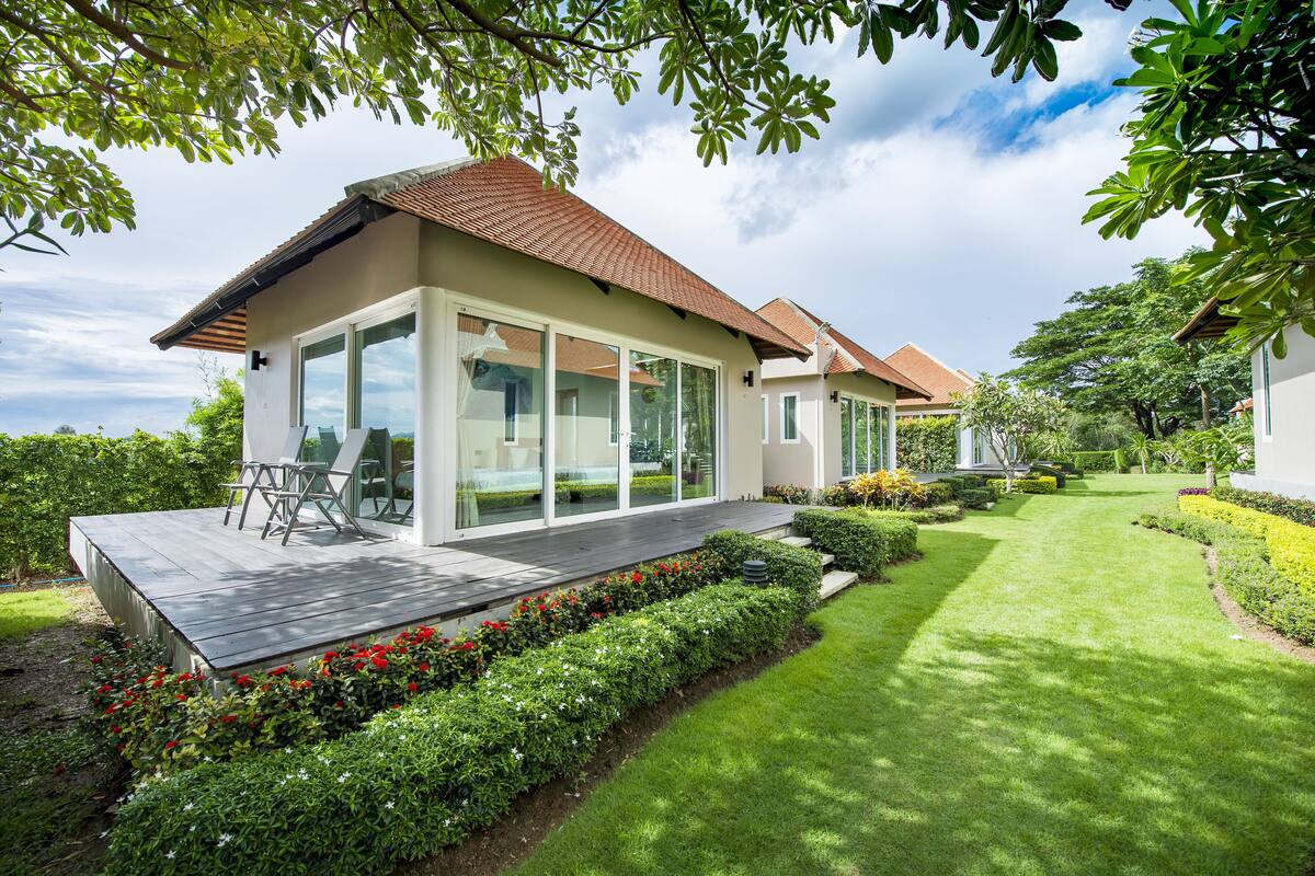 Uma casa moderna com um deck amplo, portas de vidro e um jardim bem cuidado.
