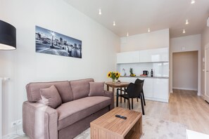 Uma sala de estar moderna com um sofá, uma mesa de centro e uma pintura de paisagem urbana na parede.