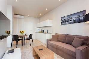Uma sala de estar moderna com um sofá, uma mesa de centro e um espaço de jantar com cadeiras e uma mesa.