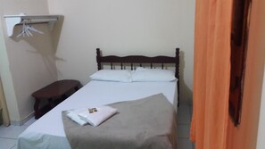 Uma cama de solteiro com roupa de cama branca, cabeceira de madeira e uma pequena mesa de cabeceira.