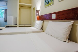 Quarto de hotel com duas camas, uma mesa pequena, um refrigerador e uma janela com cortinas.