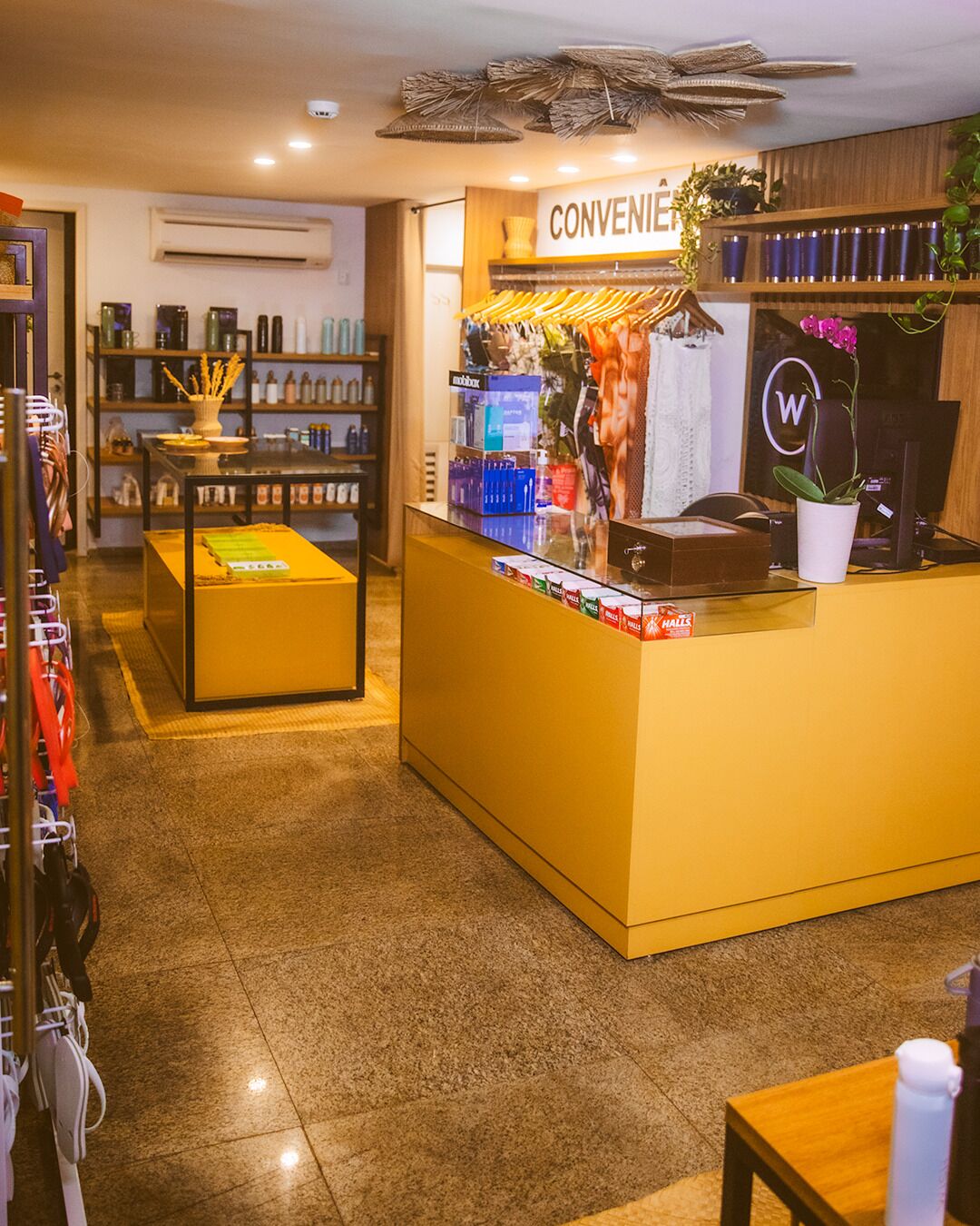 Um saguão de hotel com uma recepção, uma estante com artigos de higiene e um cabideiro.