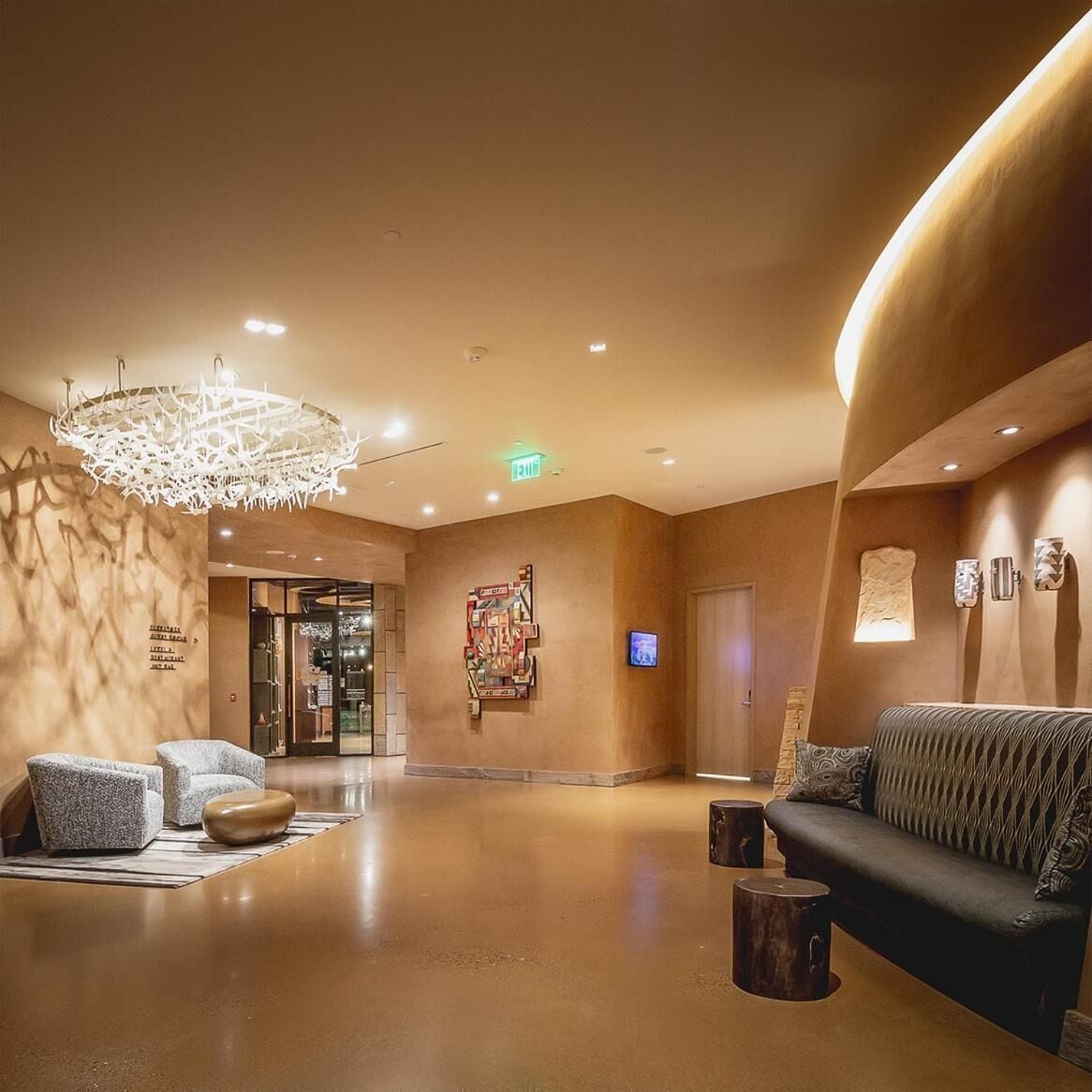 Um hall amplo com um lustre moderno, área de estar e obras de arte nas paredes.