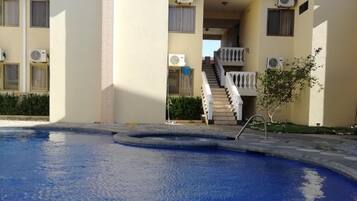 Piscina com escadaria que leva a um edifício.