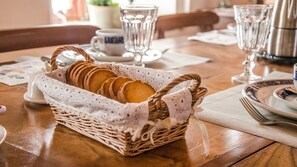 Mesa de jantar com uma cesta de vime contendo pães, uma xícara e um pires.