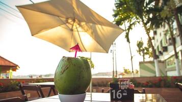 Uma mesa com uma bebida de coco, um guarda-sol e um cardápio.