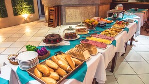 Uma mesa de buffet com diversos alimentos e uma cesta de frutas.