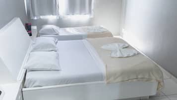 Quarto com duas camas, roupa de cama branca e janela com cortinas.
