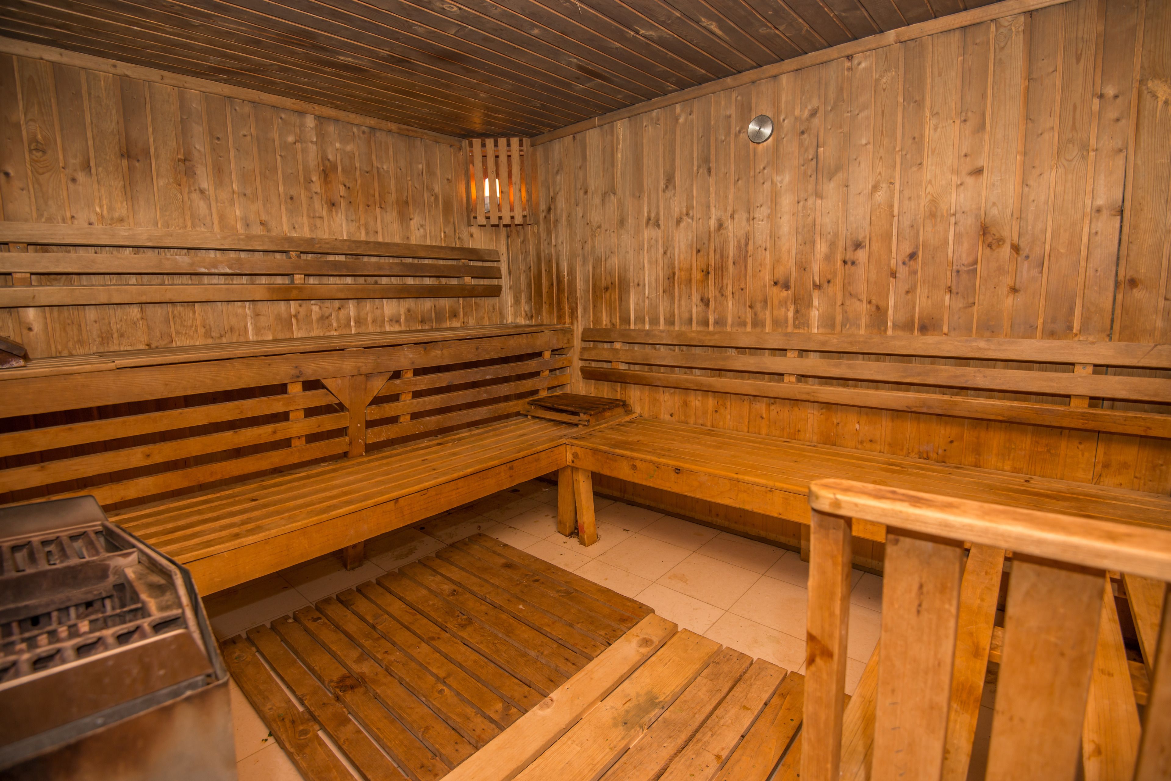 Uma sauna de madeira com bancos e um banco no chão.
