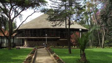 Um edifício com telhado de palha, cercado por um jardim com um caminho pavimentado.