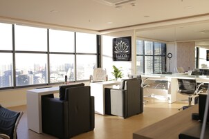 Um espaço de escritório moderno com uma janela ampla, um balcão de recepção e várias áreas de estar.