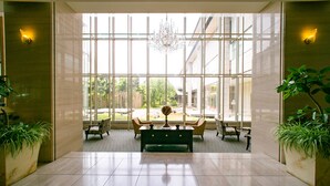 Um hall amplo com uma janela grande, um candelabro e dois sofás.