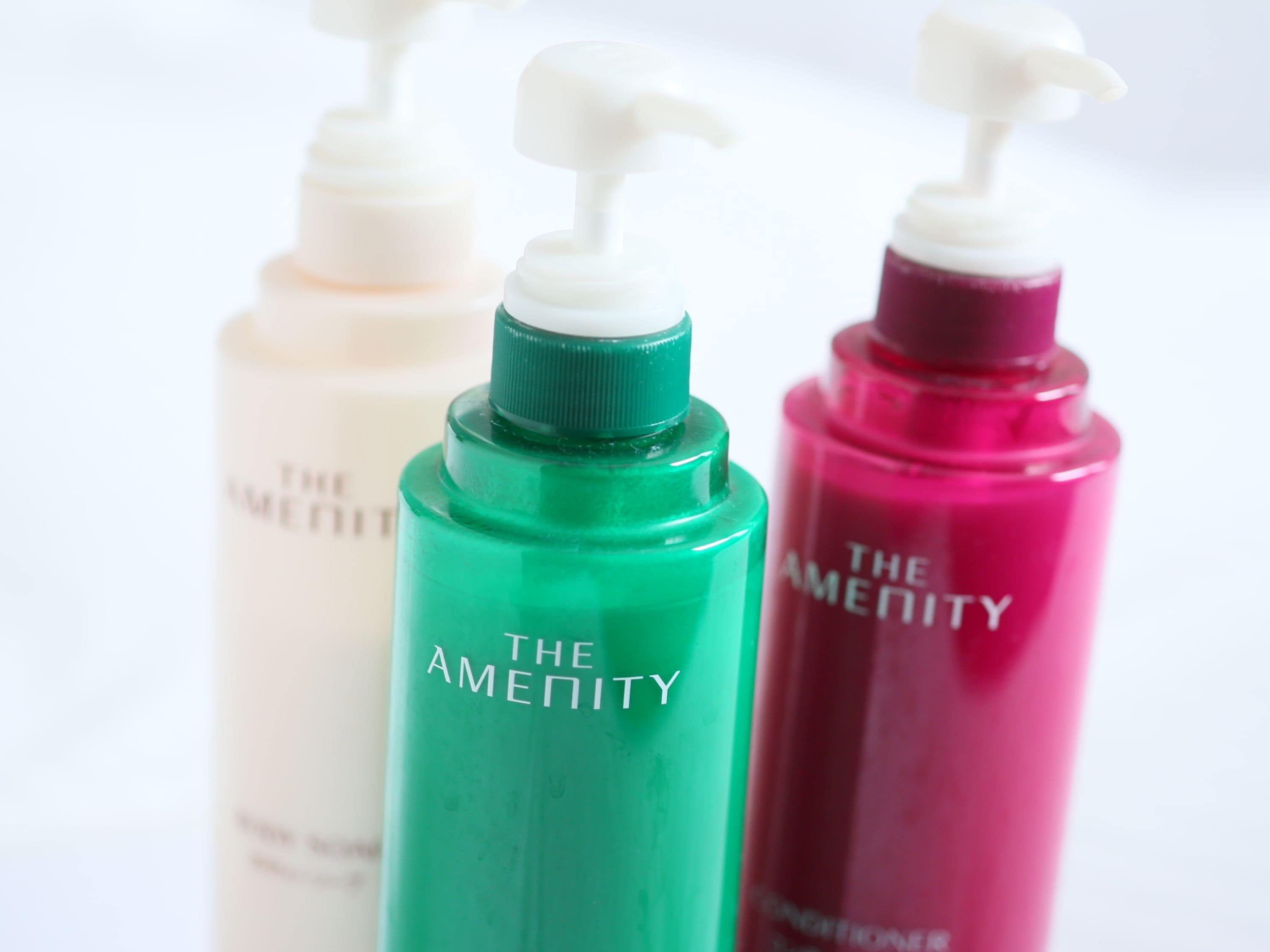 Três frascos de shampoo da marca The Amenity.