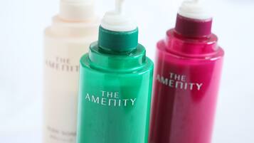 Três frascos de shampoo da marca The Amenity.