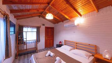 Quarto com painéis de madeira, uma cama, uma mesinha de cabeceira, uma prateleira e uma janela com cortinas.