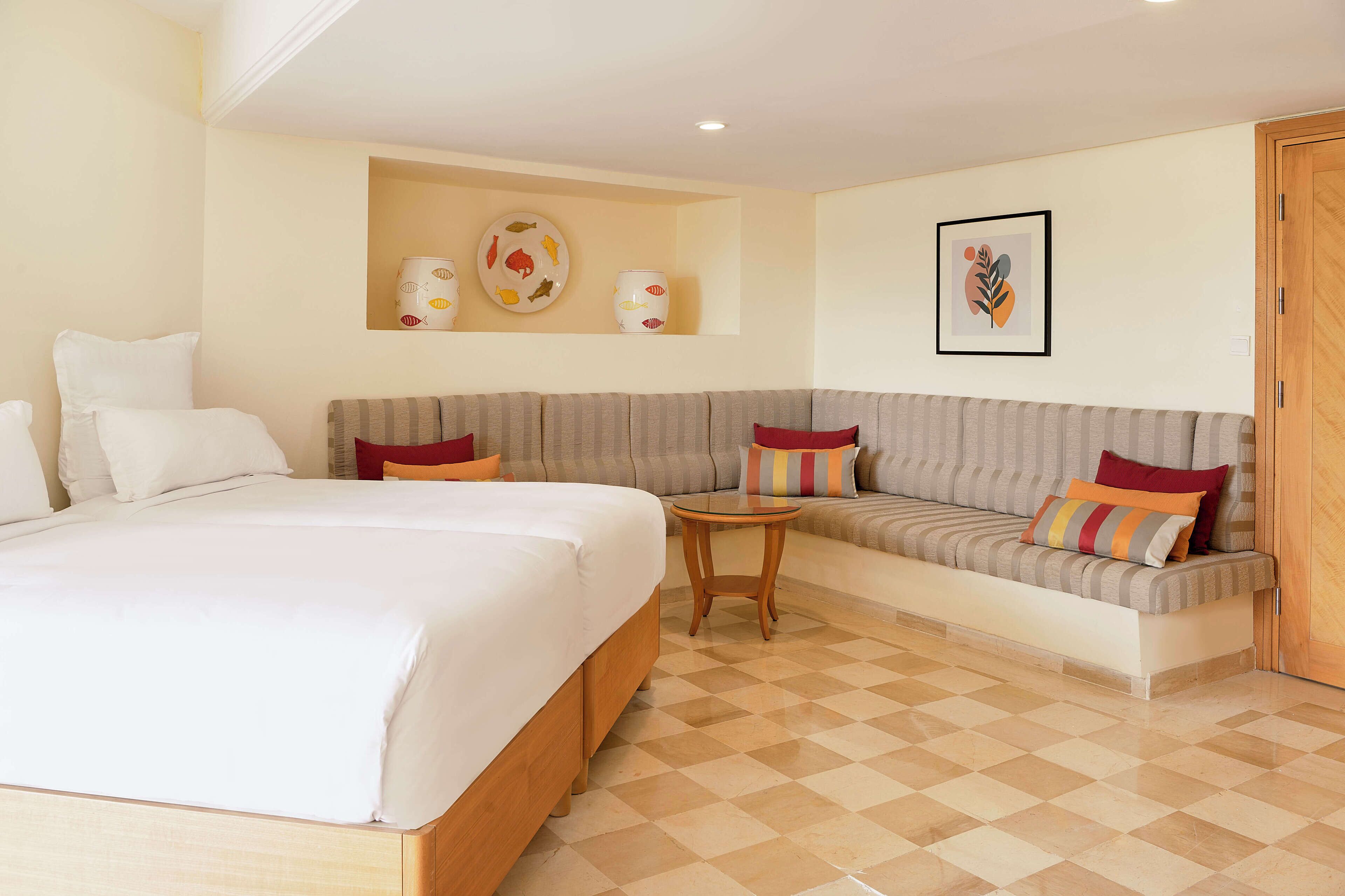 Quarto de hotel com uma cama grande, um sofá, uma mesinha e uma parede decorada.