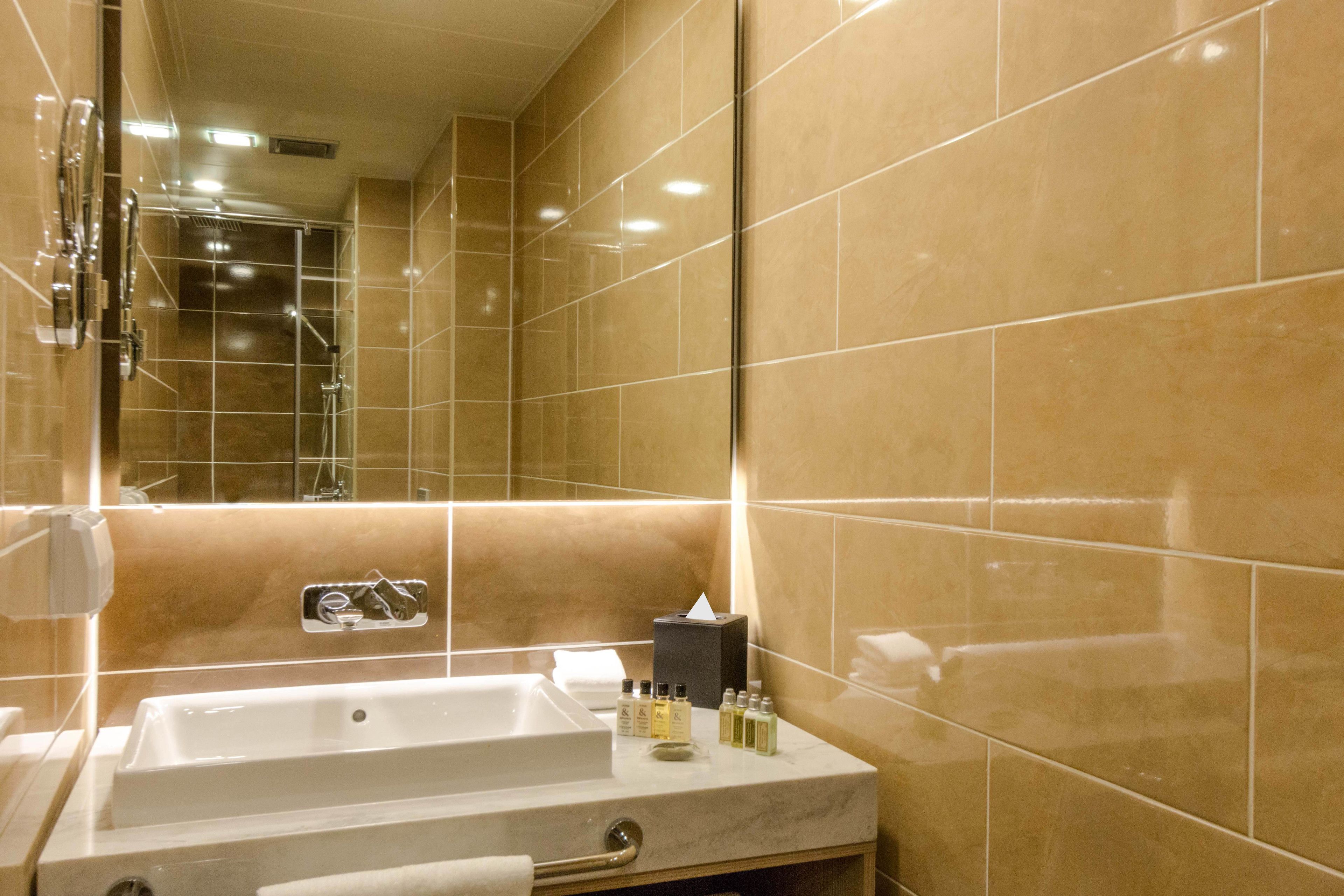 Um banheiro moderno com uma pia grande, espelho e amenities.