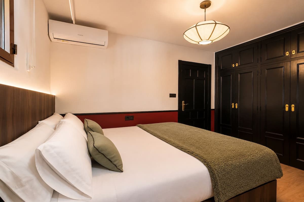 Quarto de hotel com cama, ar condicionado, porta e guarda-roupa.