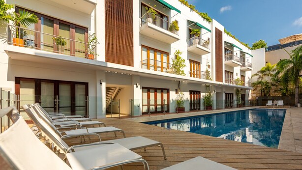 Um hotel moderno com área de piscina, espreguiçadeiras e uma escadaria que dá acesso aos andares superiores.