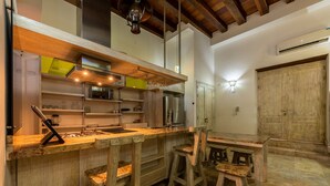 Uma cozinha rústica com banquetas de madeira, fogão embutido e luminária pendente.