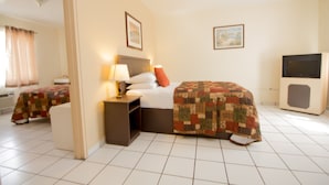 Quarto de hotel com cama, mesa de cabeceira, abajur e televisão.