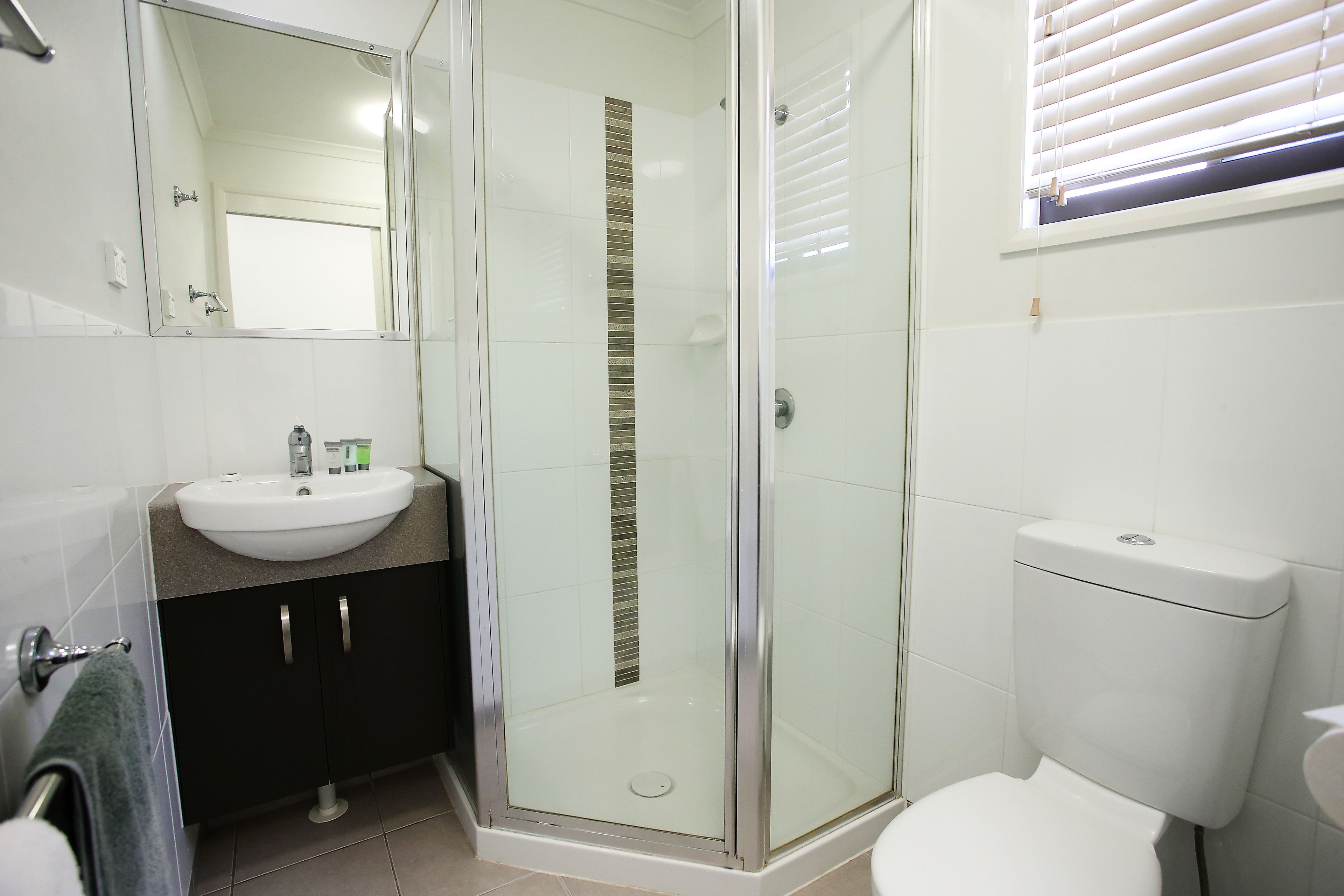 Uma casa de banho moderna com cabine de duche em vidro, lavatório branco e sanita.