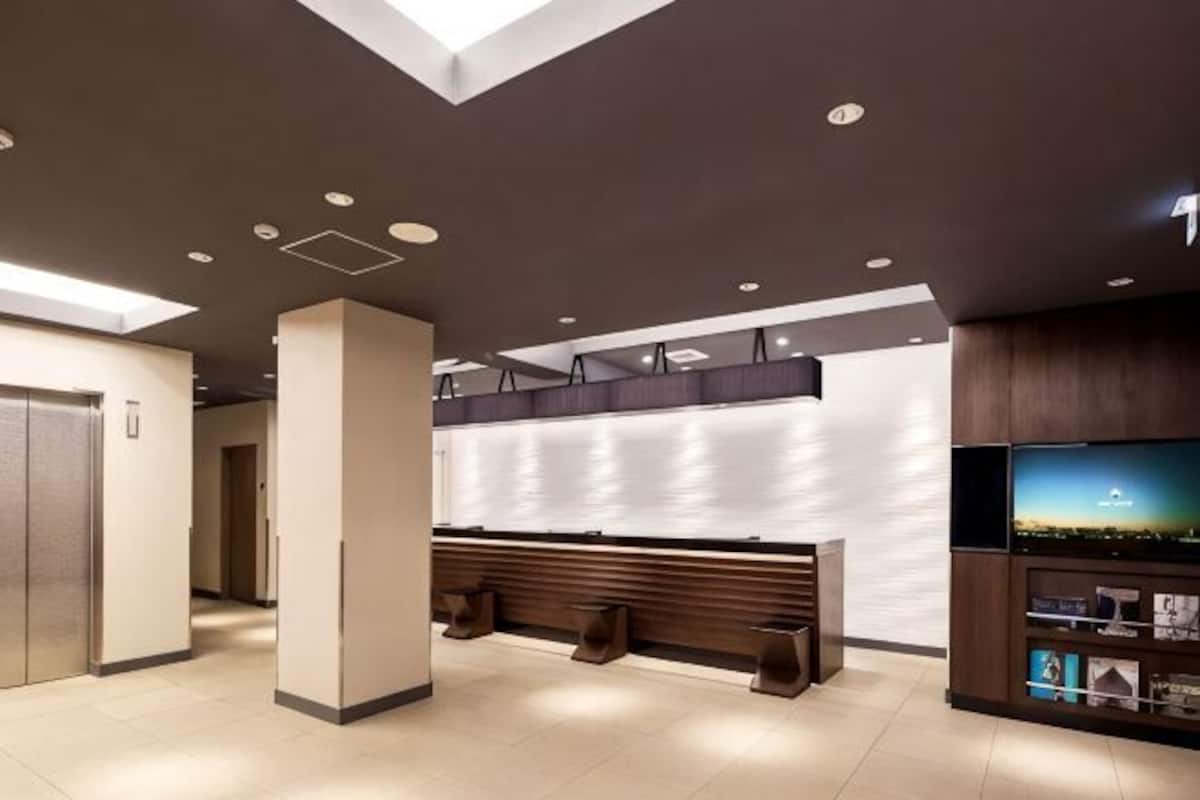 Um lobby moderno com balcão de recepção, área de estar e uma grande televisão de tela plana.