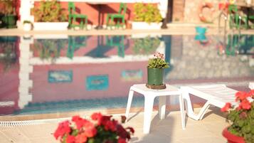 Uma área de piscina com vista desimpedida, uma cadeira branca e plantas em vasos.